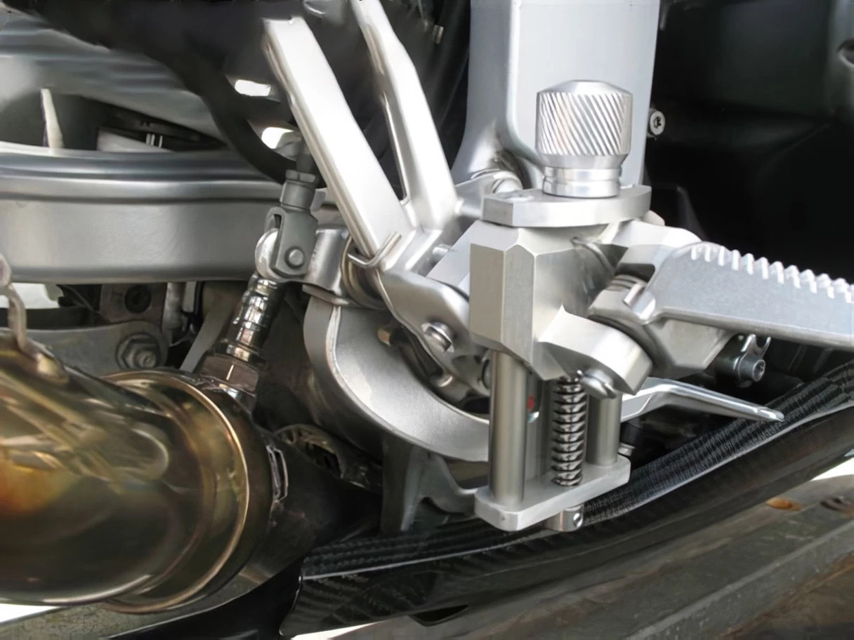 Maintenance-free linear adjustment of footrests on the motorbike